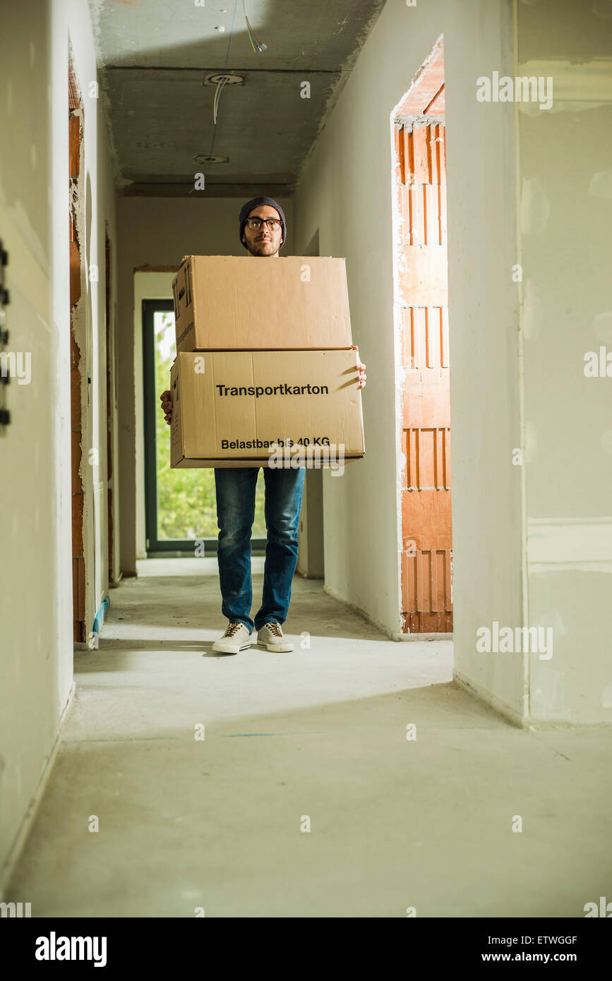 Young man carrying cardboard boxes in hallway Stock Photo - Alamy