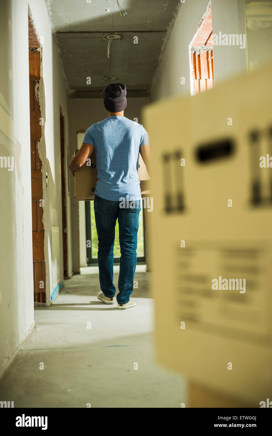 Young man carrying cardboard box in hallway Stock Photo - Alamy