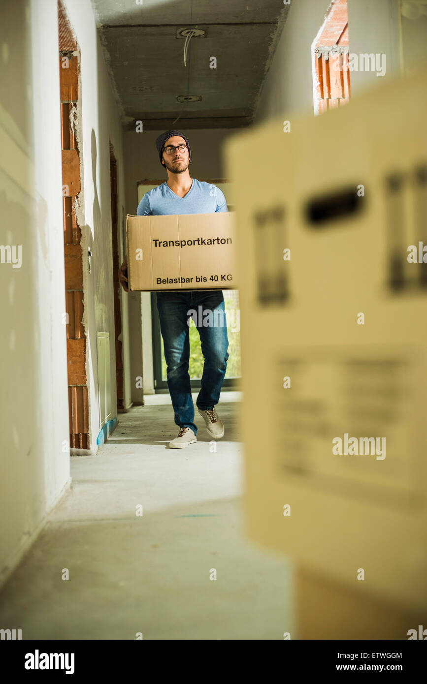Young man carrying cardboard box in hallway Stock Photo - Alamy