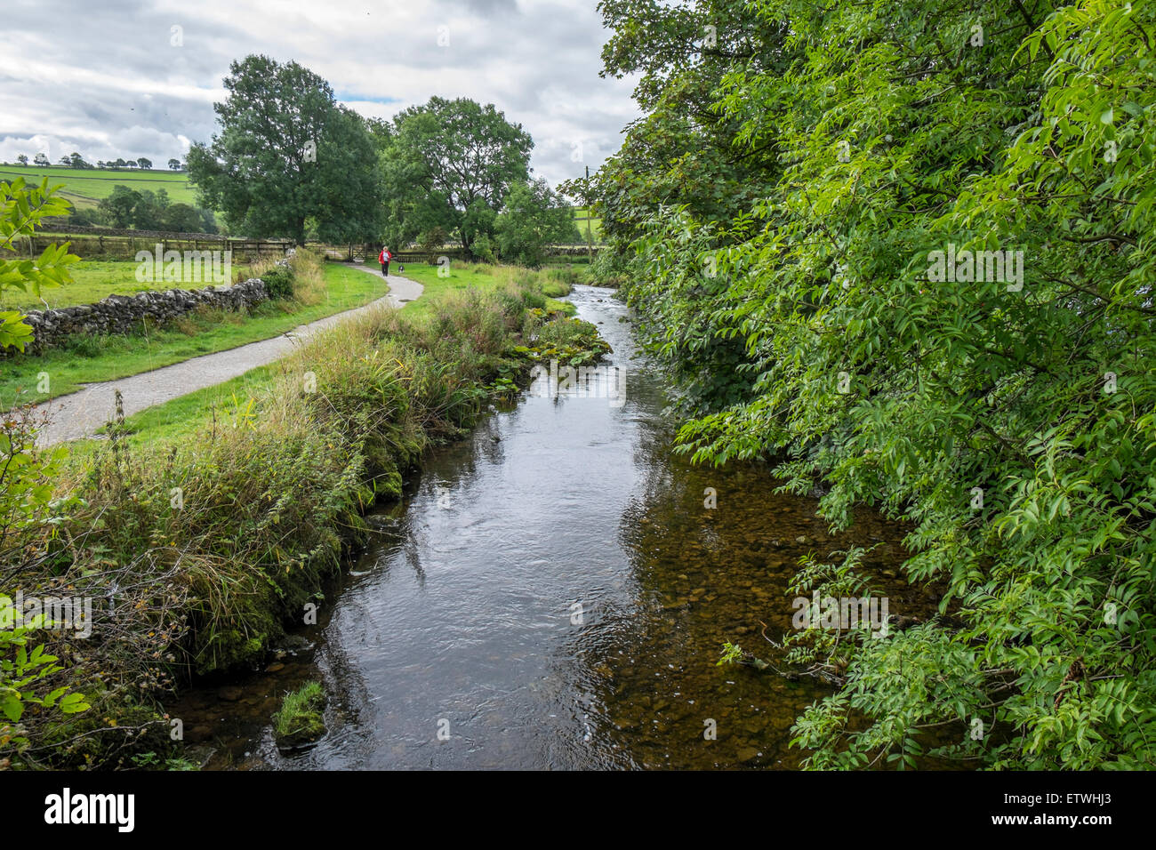A small river running through the countryside with pedestrians walking ...