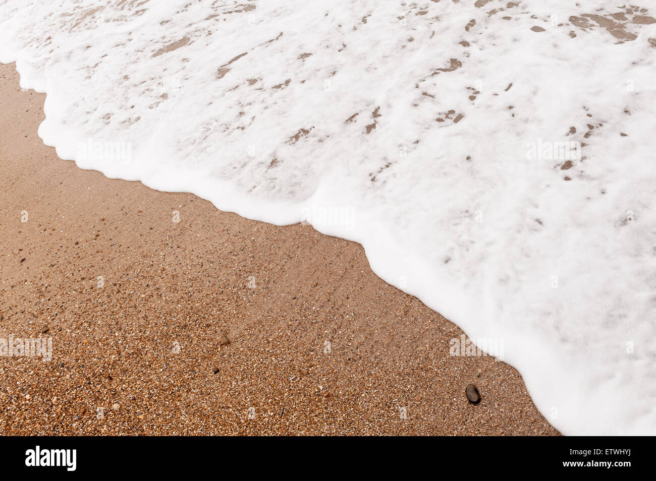 Low tide ripples wave patterns in shallow frothy bubbly sea water as it ...