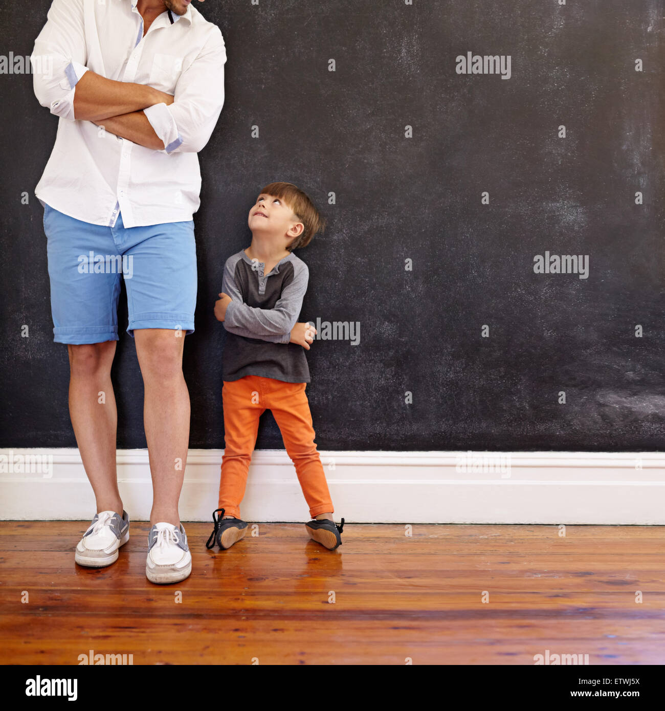 Indoor shot of little boy and his father standing with hands folded ...