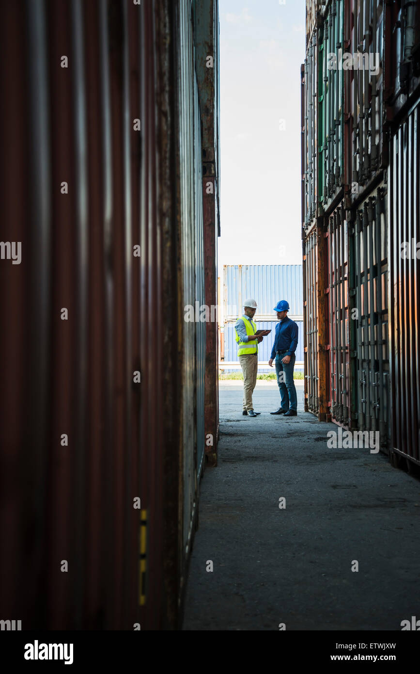 Two men with safety helmets talking at container port Stock Photo - Alamy