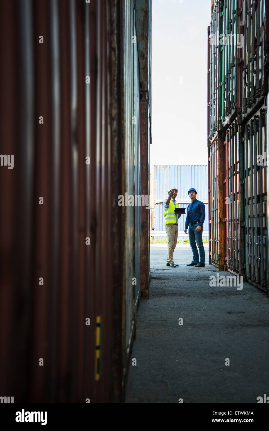Two men with safety helmets talking at container port Stock Photo - Alamy