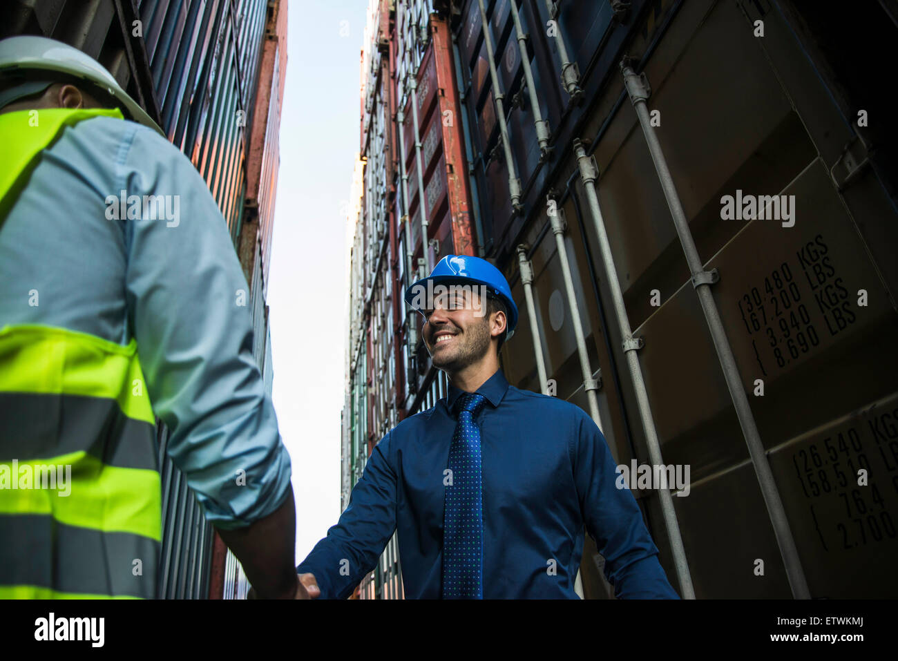 Two men with safety helmets at container port shaking hands Stock Photo ...