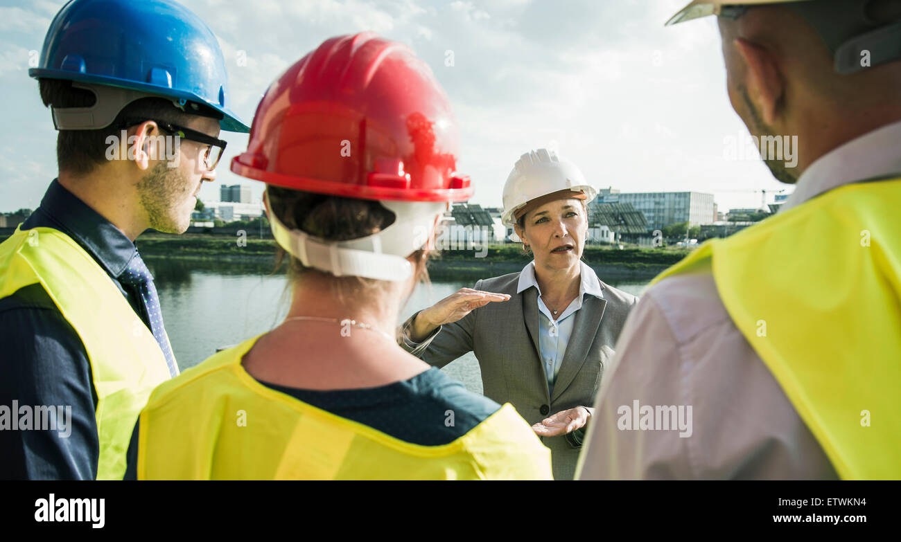 Businesswoman talking to people with safety helmets at riverside Stock ...