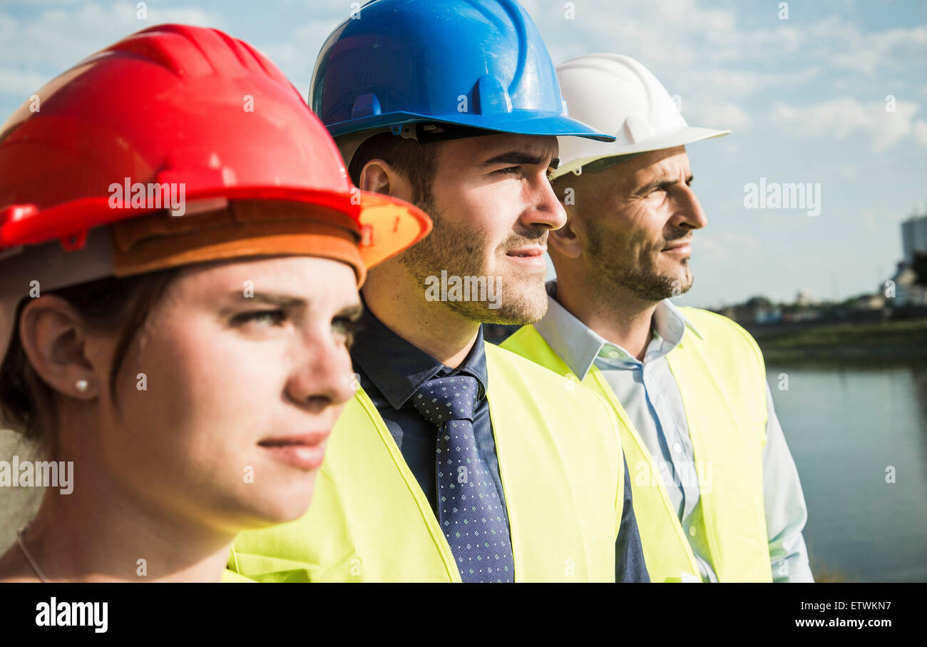 Woman and two men with safety helmets talking at riverside Stock Photo ...