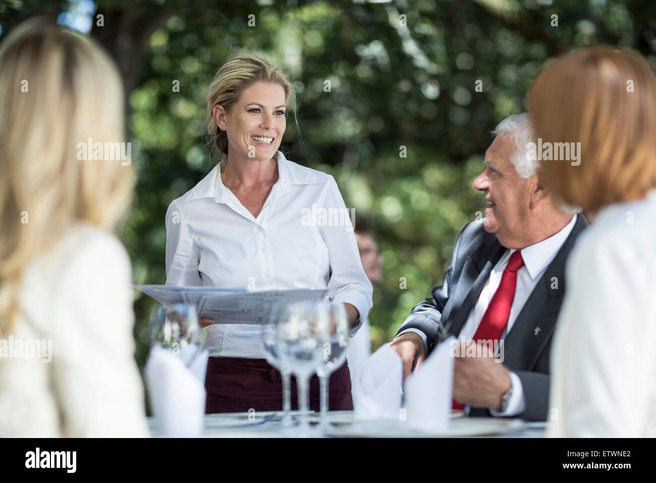 Waitress giving menus to clients at table Stock Photo - Alamy
