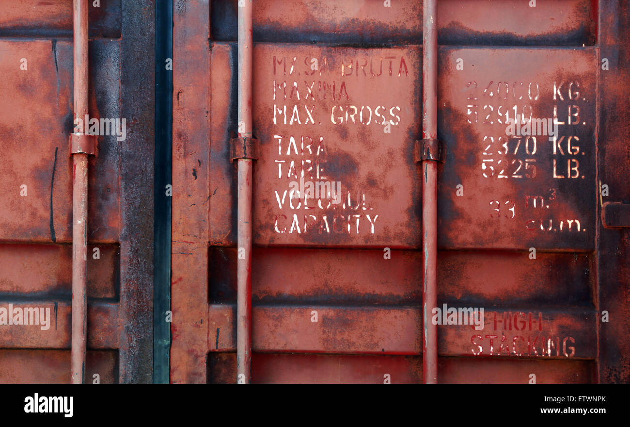 Old red shipping container door with technical characteristics text ...