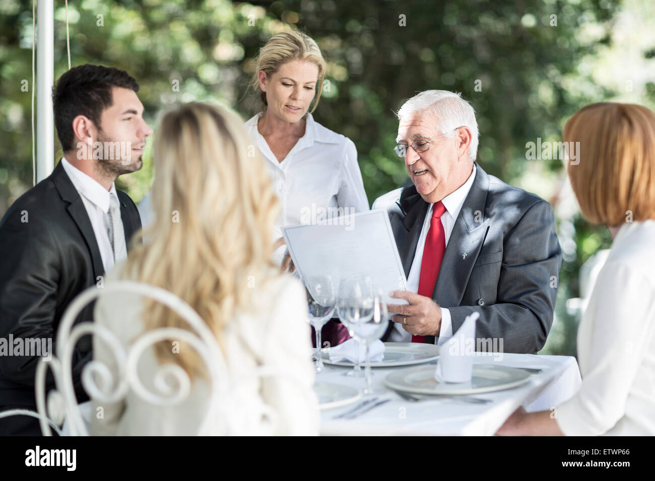 Waitress explaining menu to clients at table Stock Photo - Alamy