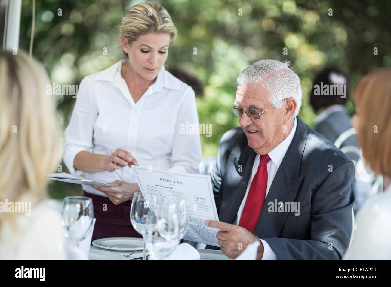 Waitress explaining menu to clients at table Stock Photo - Alamy