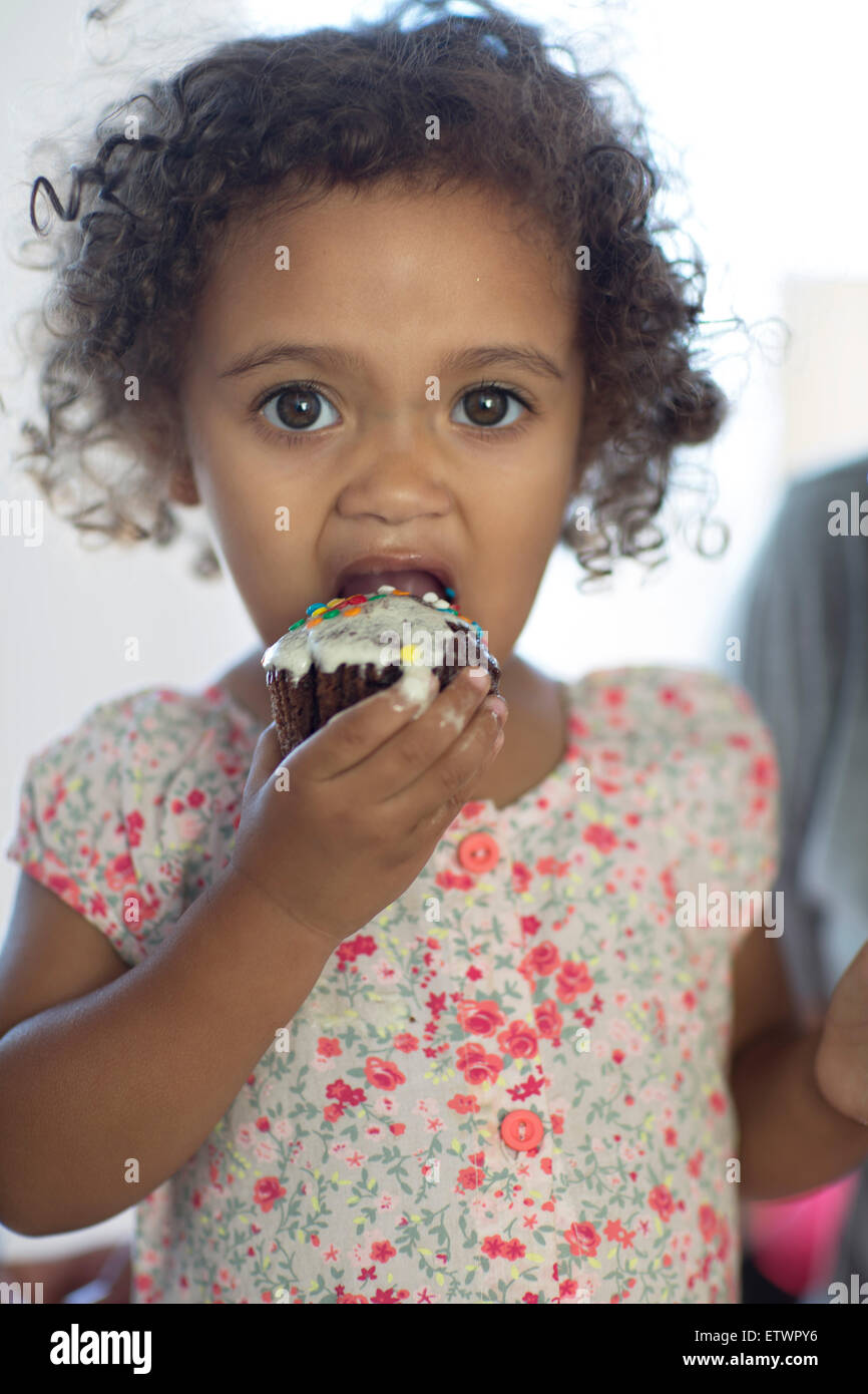 Mixed race girl eating cup cake Stock Photo - Alamy
