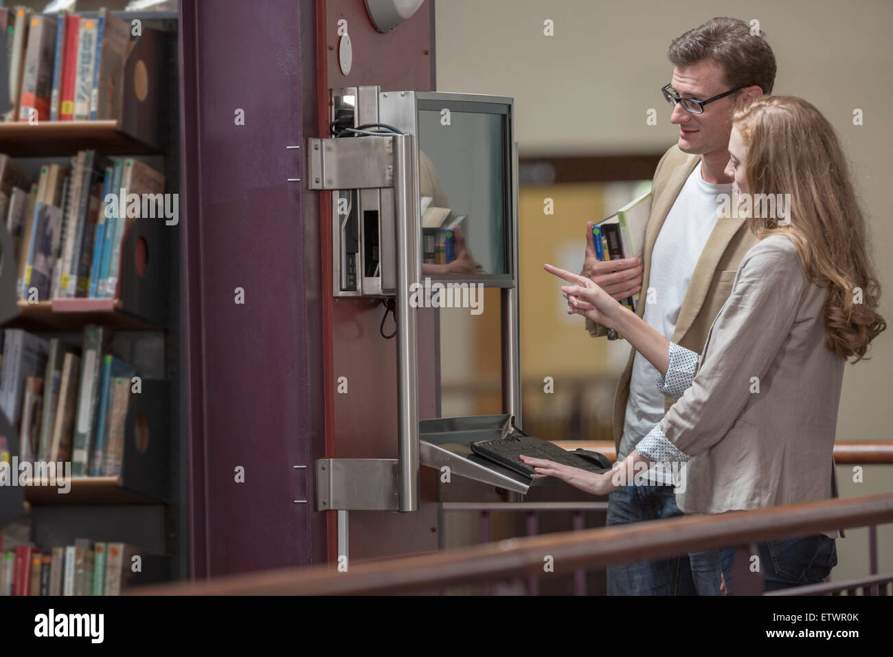 Two students looking at display screen in a library Stock Photo - Alamy