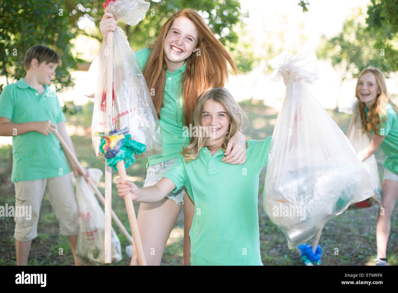 Smiling children picking up garbage in a park Stock Photo - Alamy