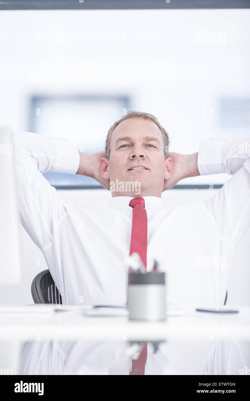 Confident businessman in office leaning back Stock Photo - Alamy