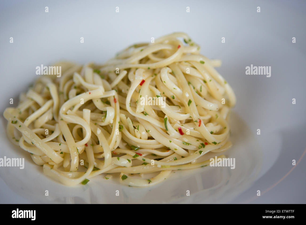 Linguini pasta with fresh chili flakes and olive oil served in a white ...