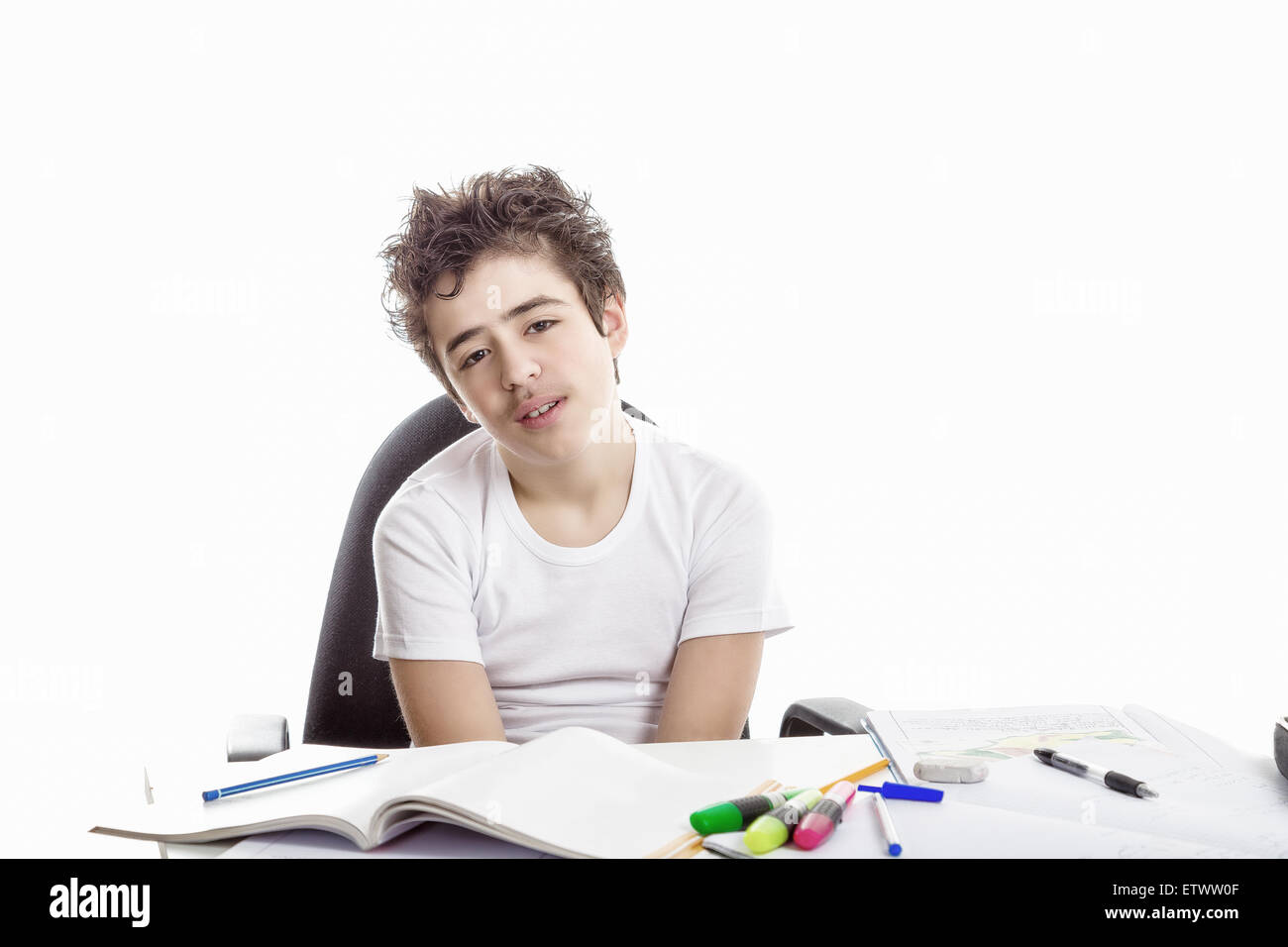 Tired boy doing his homework: he is sadly sitting in front of books ...