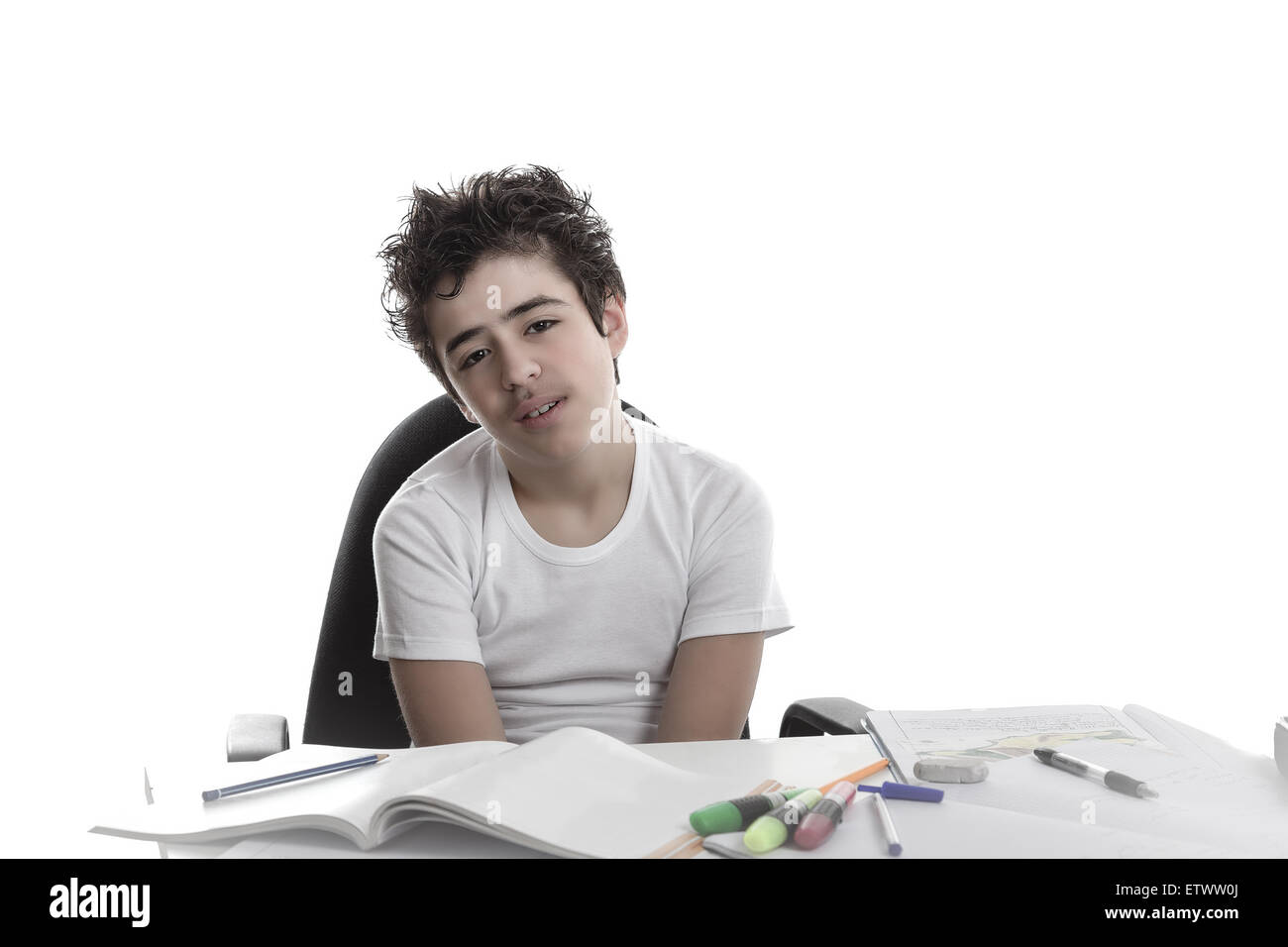 Tired boy doing his homework: he is sadly sitting in front of books ...