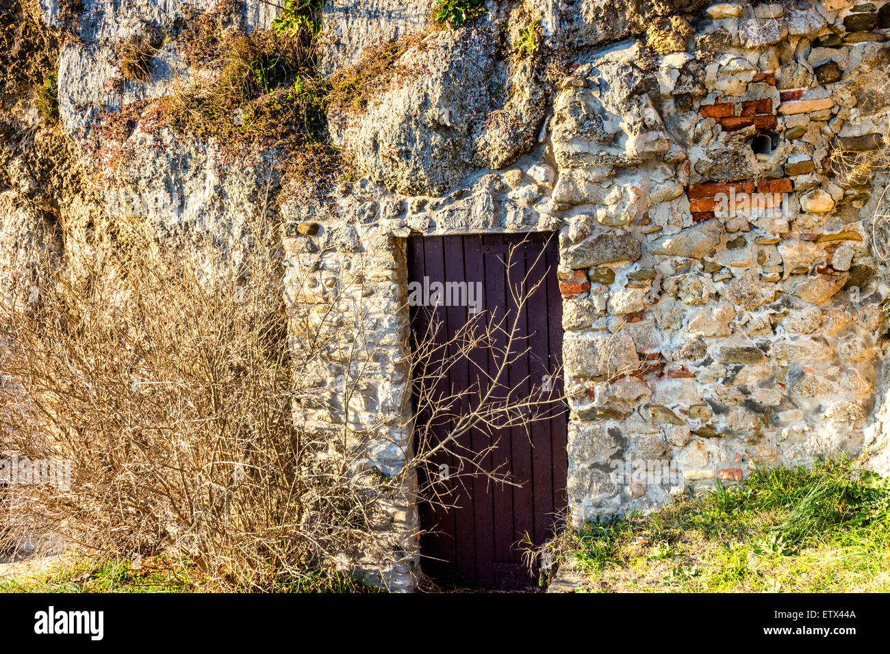 wooden square door of an ancient fortress with white stone walls in ...
