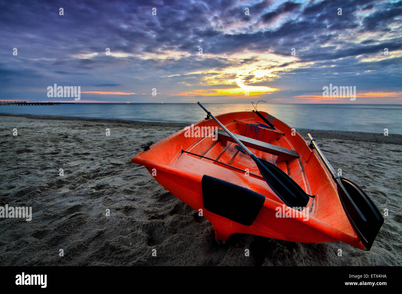 Orange boat on the ocean beach -at dramatic sunrise clouds sky Stock ...