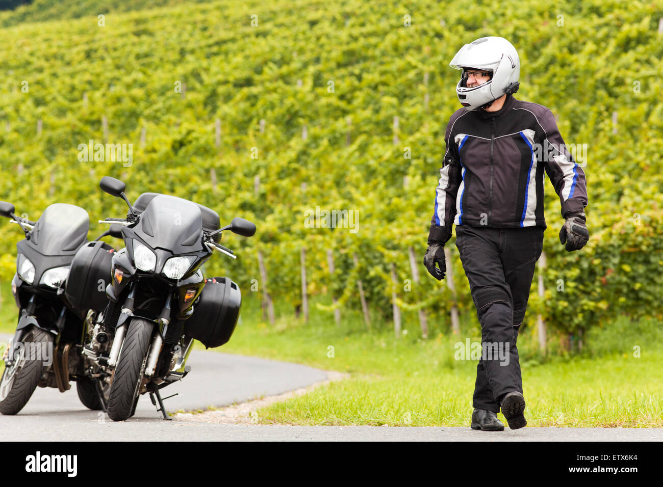 Motorcyclist with helmet walkes on the road Stock Photo - Alamy