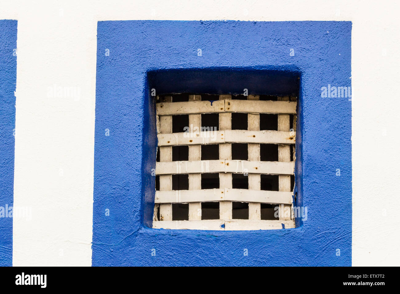Square window with bright blue painted border and wood grate on white ...