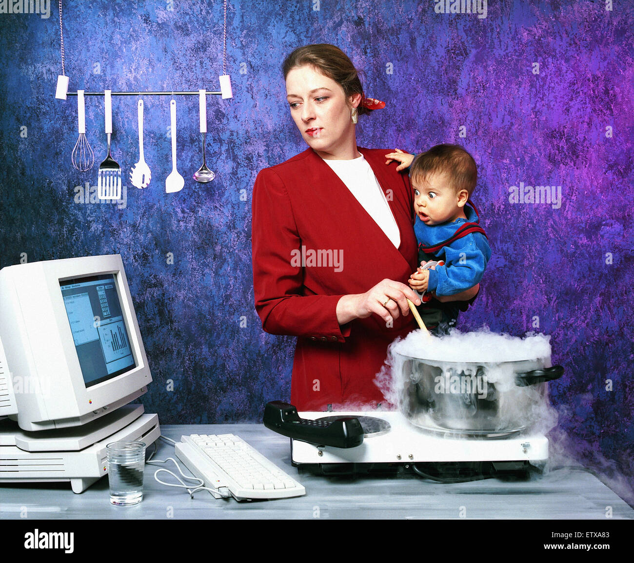 Hamburg, Germany, Cooking Mama with baby in her arms looking at ...