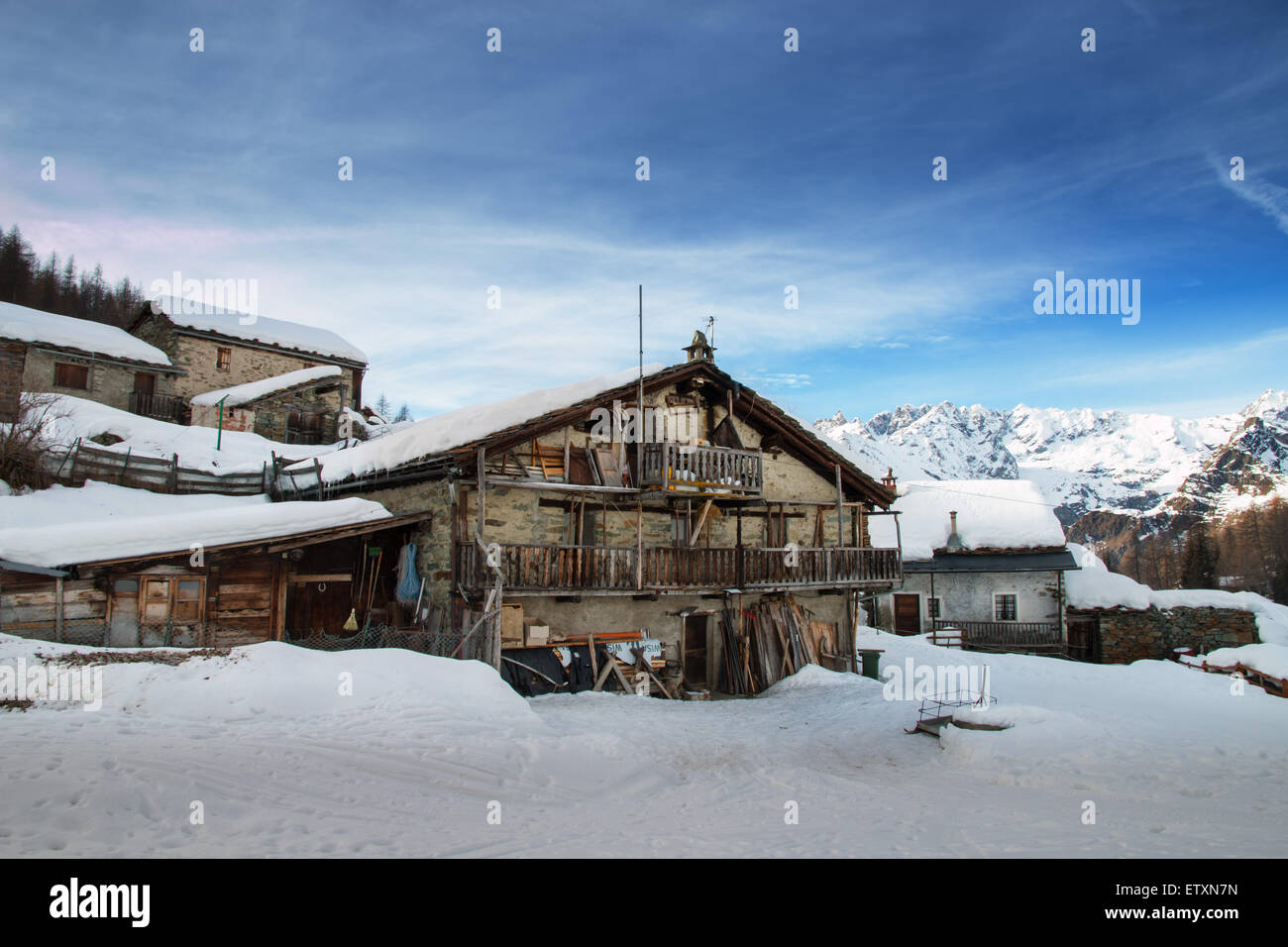typical old chalet made of stone and wood in Italian Alps under snow ...