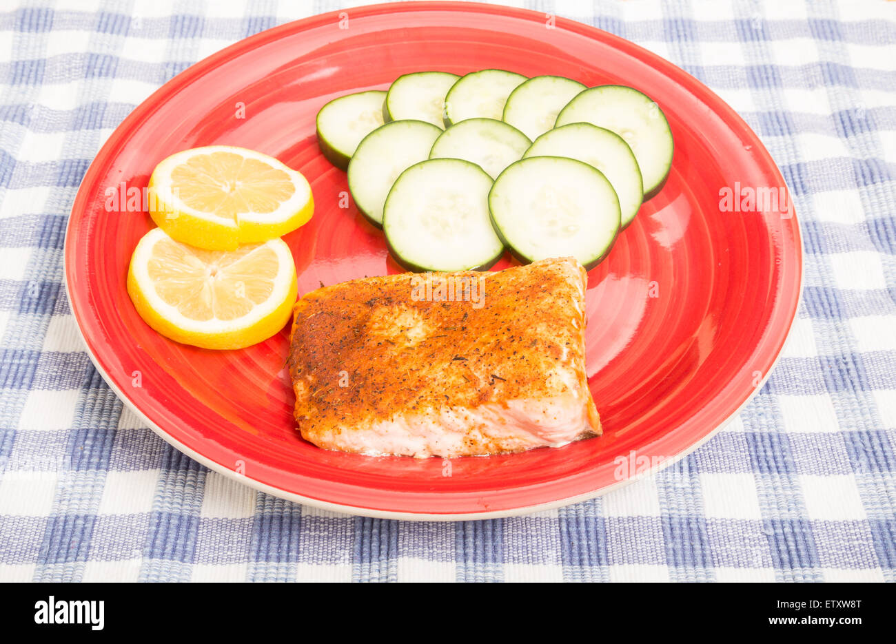A baked piece of fresh atlantic salmon on a red plate with sliced ...
