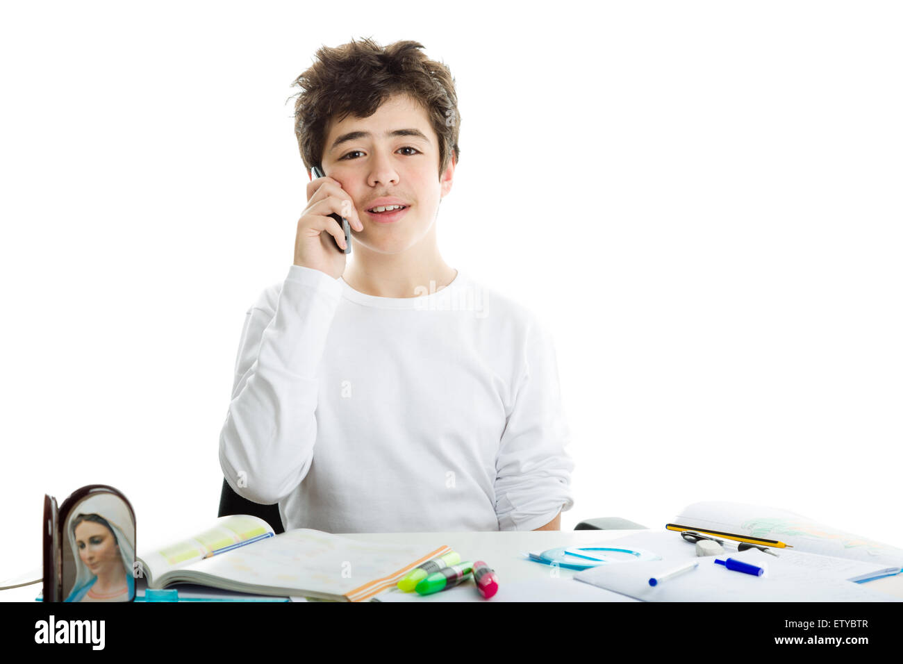 Smiling handsome Hispanic boy is talking on cell phone while doing ...