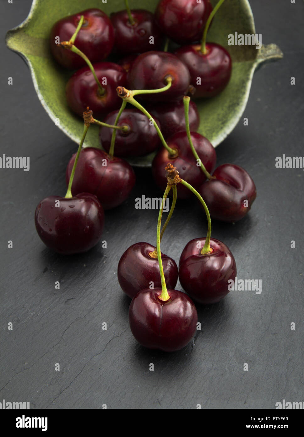 dark red cherries on a black slate surface Stock Photo - Alamy