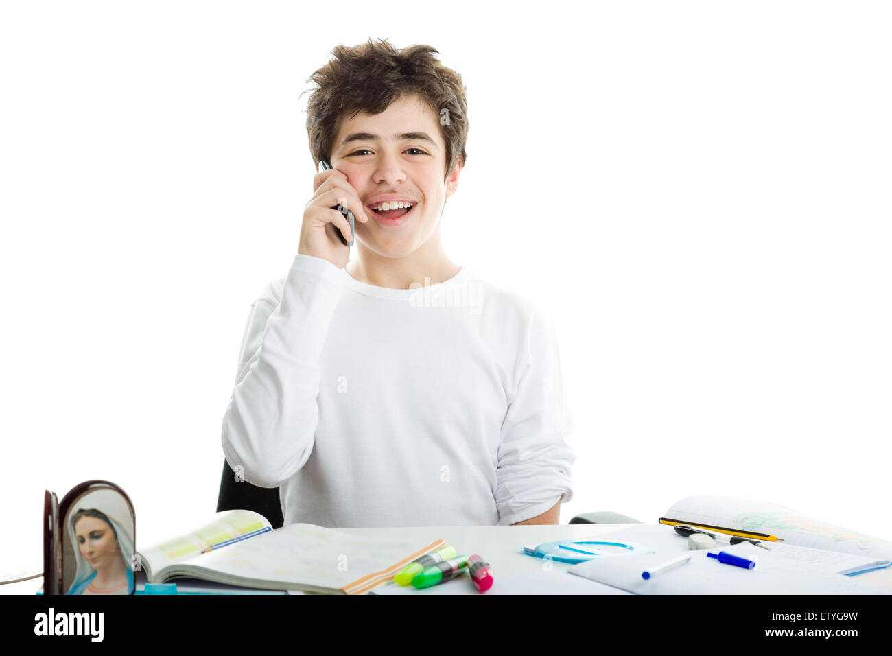 Smiling handsome Hispanic boy is talking on mobile phone while doing ...