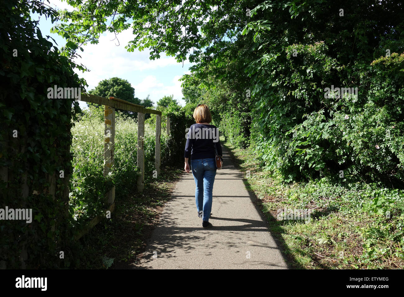 Back view of woman walking along footpath in park Stock Photo - Alamy