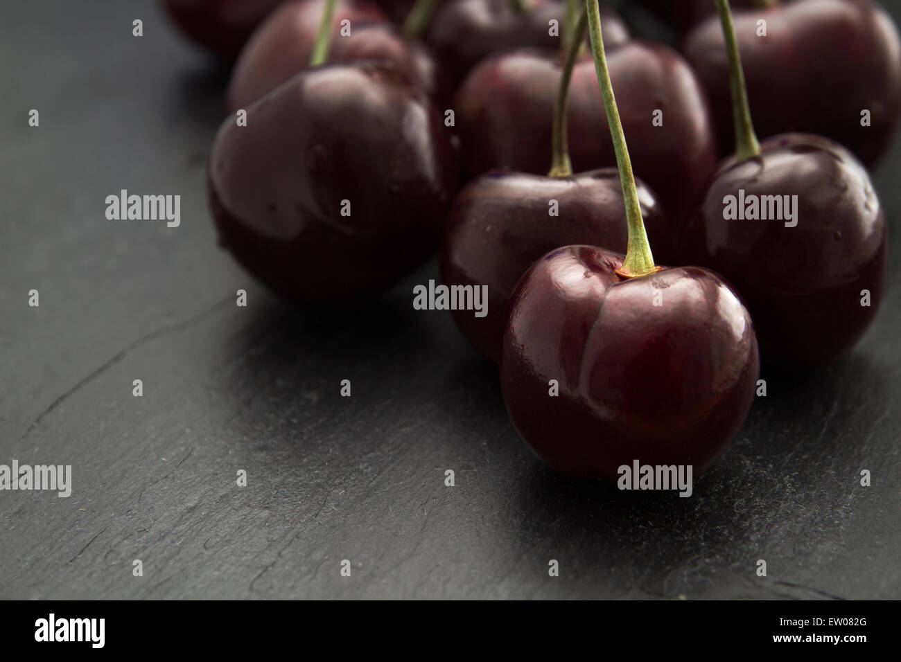 dark red cherries on a black slate surface Stock Photo - Alamy