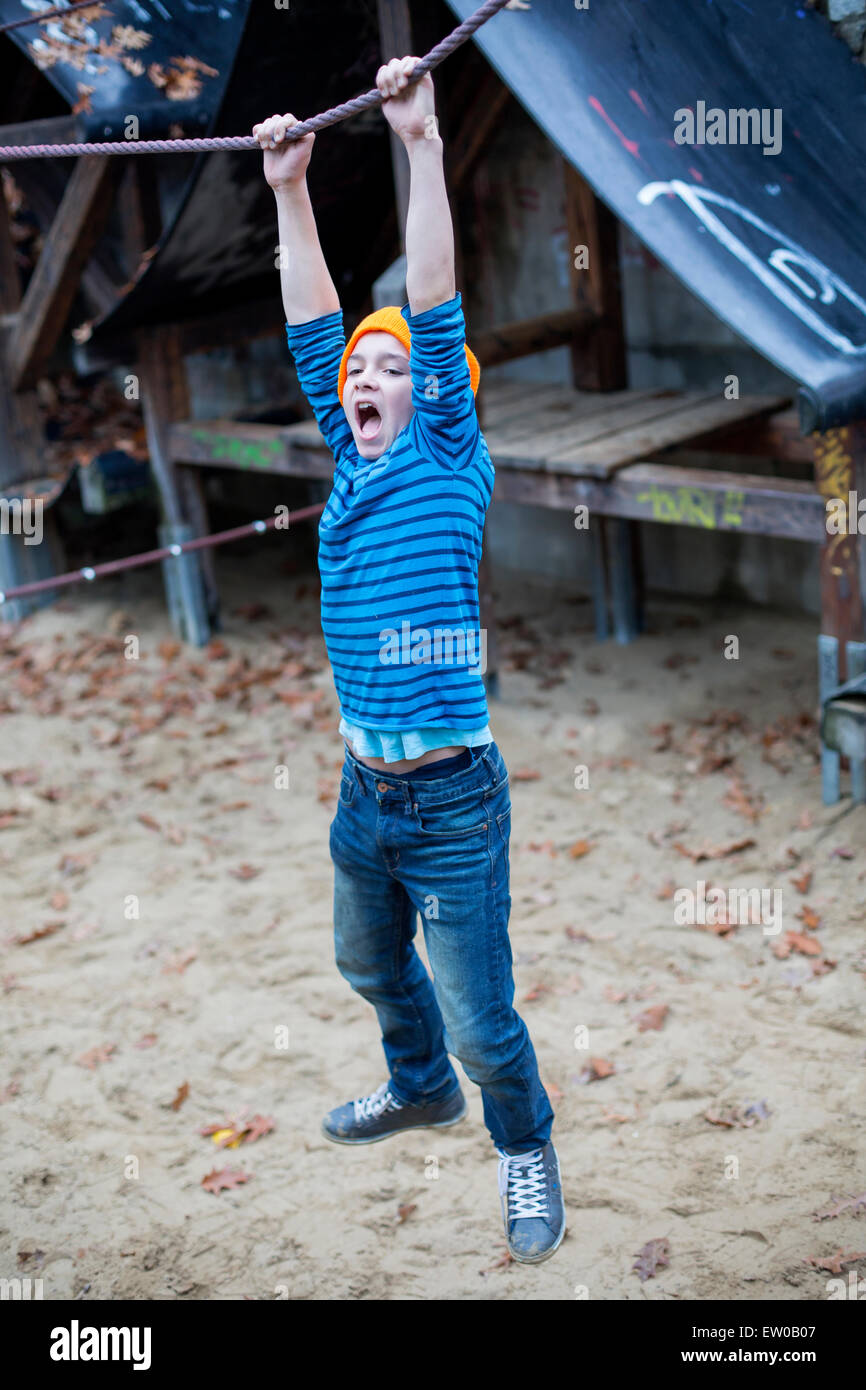 young boy outside on playground hanging on a rope Stock Photo - Alamy