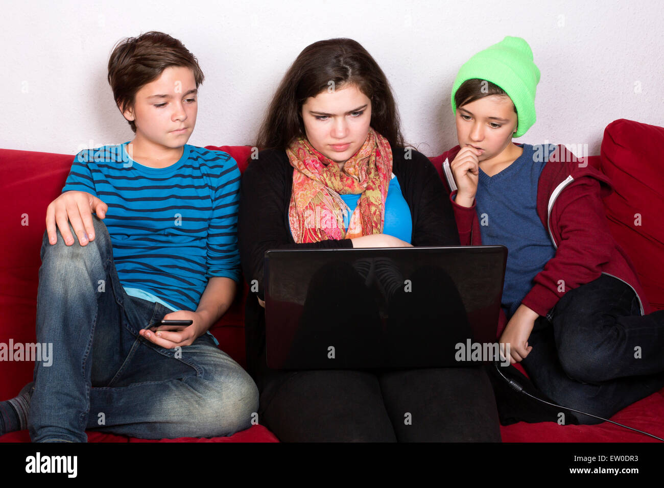 teenage girl and two boys looking at a laptop Stock Photo - Alamy
