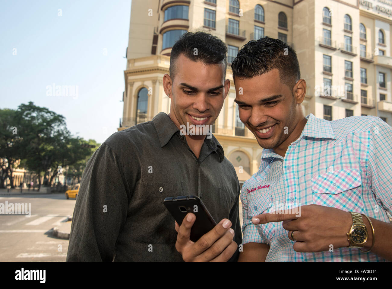 Two Latin friends using cell phone outdoors Stock Photo - Alamy