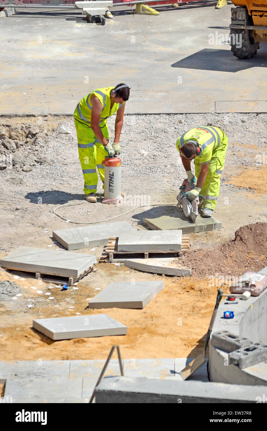 London, England, UK. Workers cutting concrete slabs for paving, by the ...