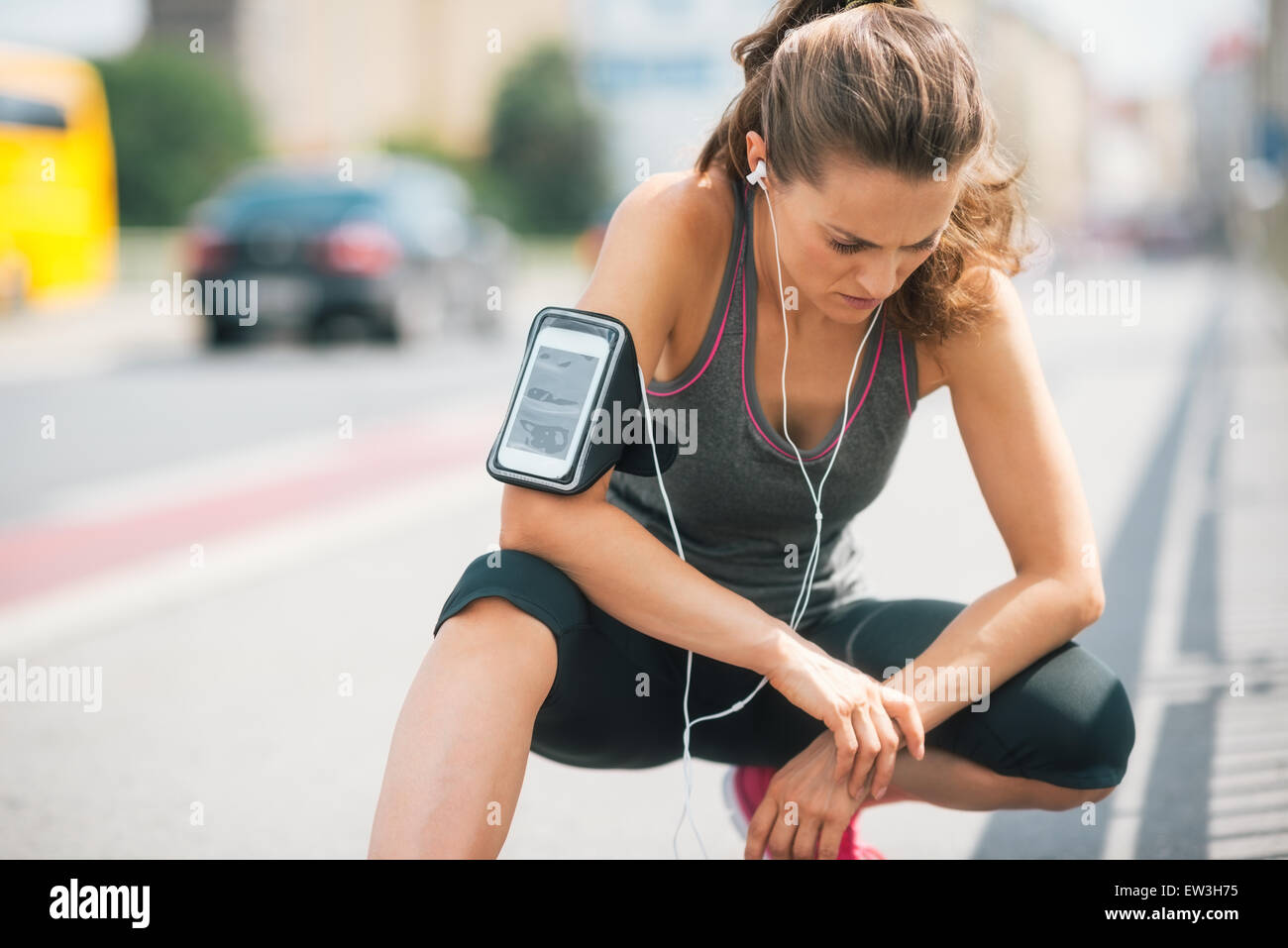 An athletic woman wearing earbuds and her device in a cuff on her arm ...