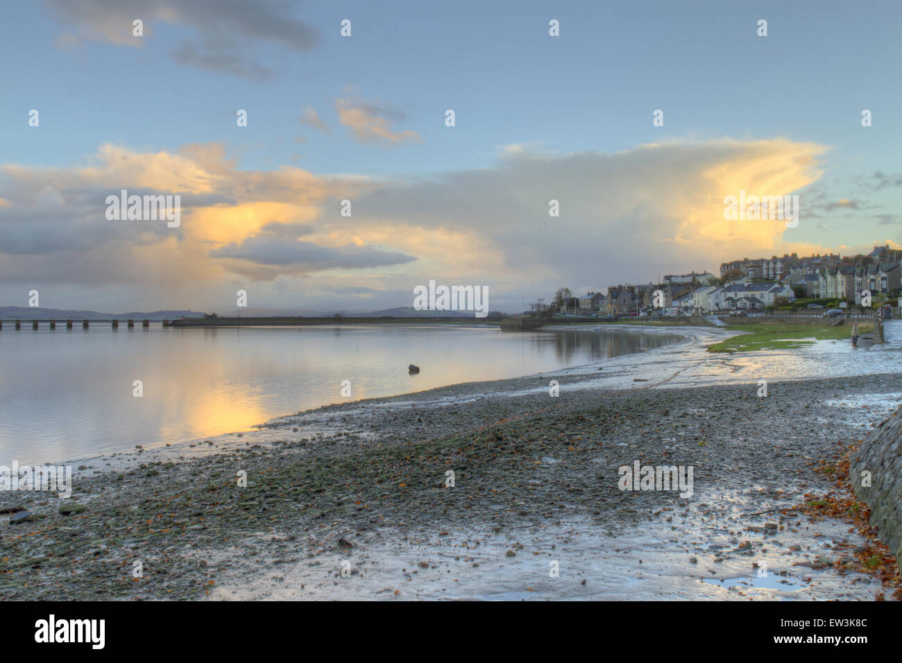View of village seafront and viaduct across river estuary in early ...