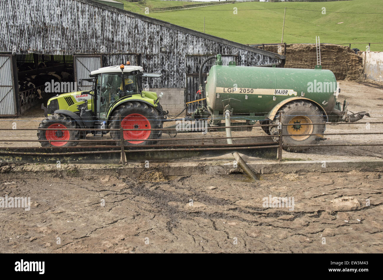Claas tractor with slurry tanker, loading slurry from lagoon, near ...
