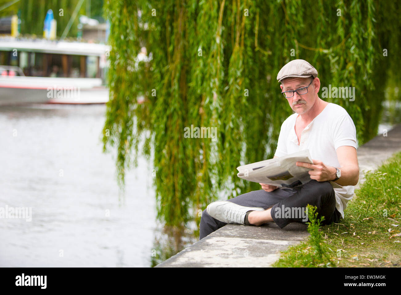 man sitting by the water and reading a newspaper Stock Photo - Alamy