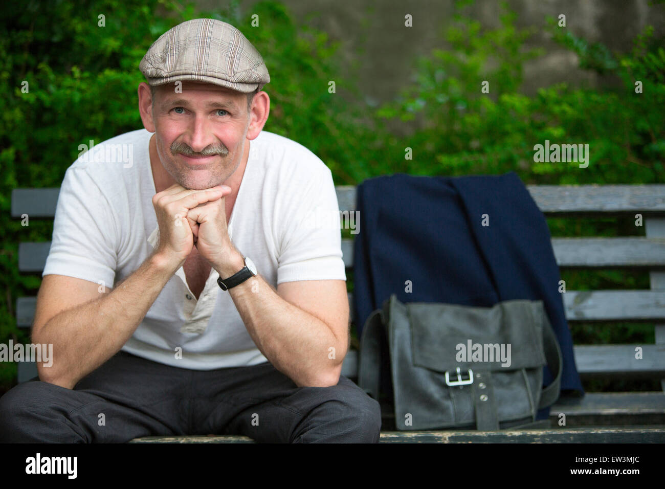 portrait of a man sitting on a bench in a park Stock Photo - Alamy
