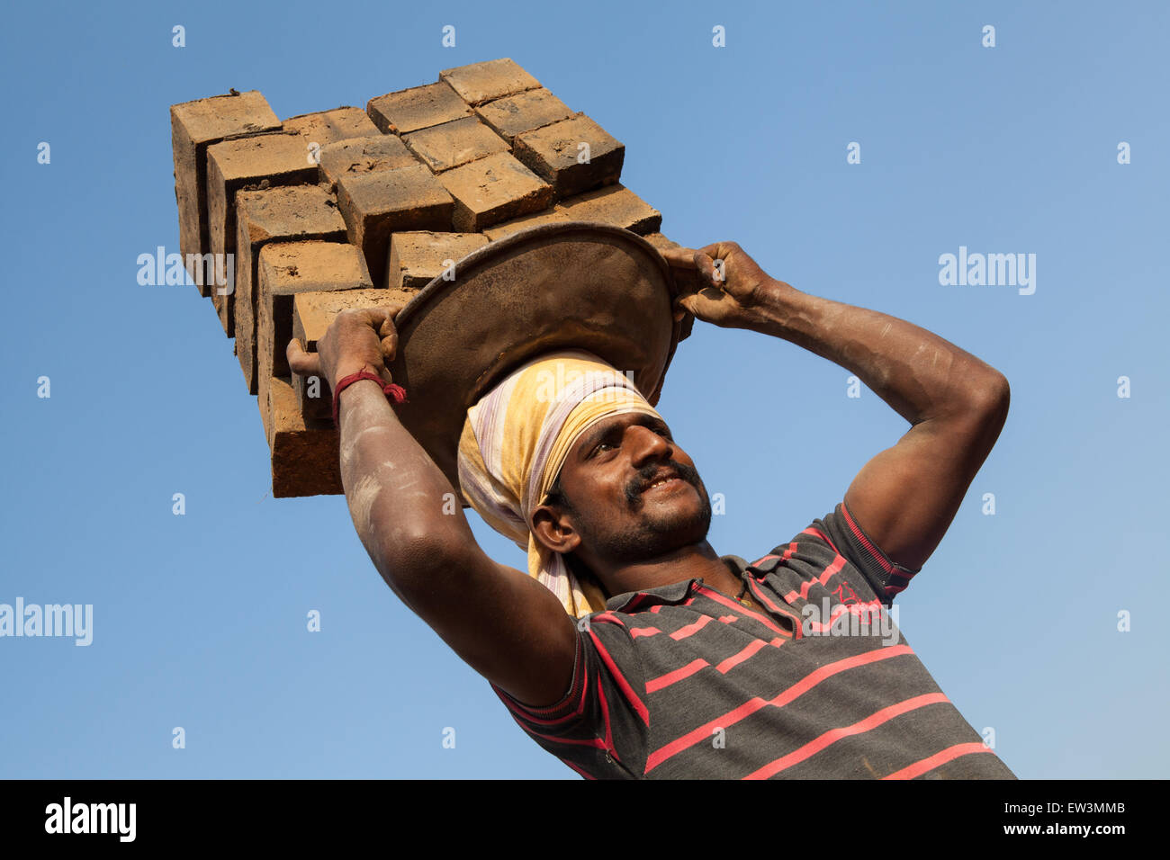 Male worker carrying bricks on his head Stock Photo - Alamy