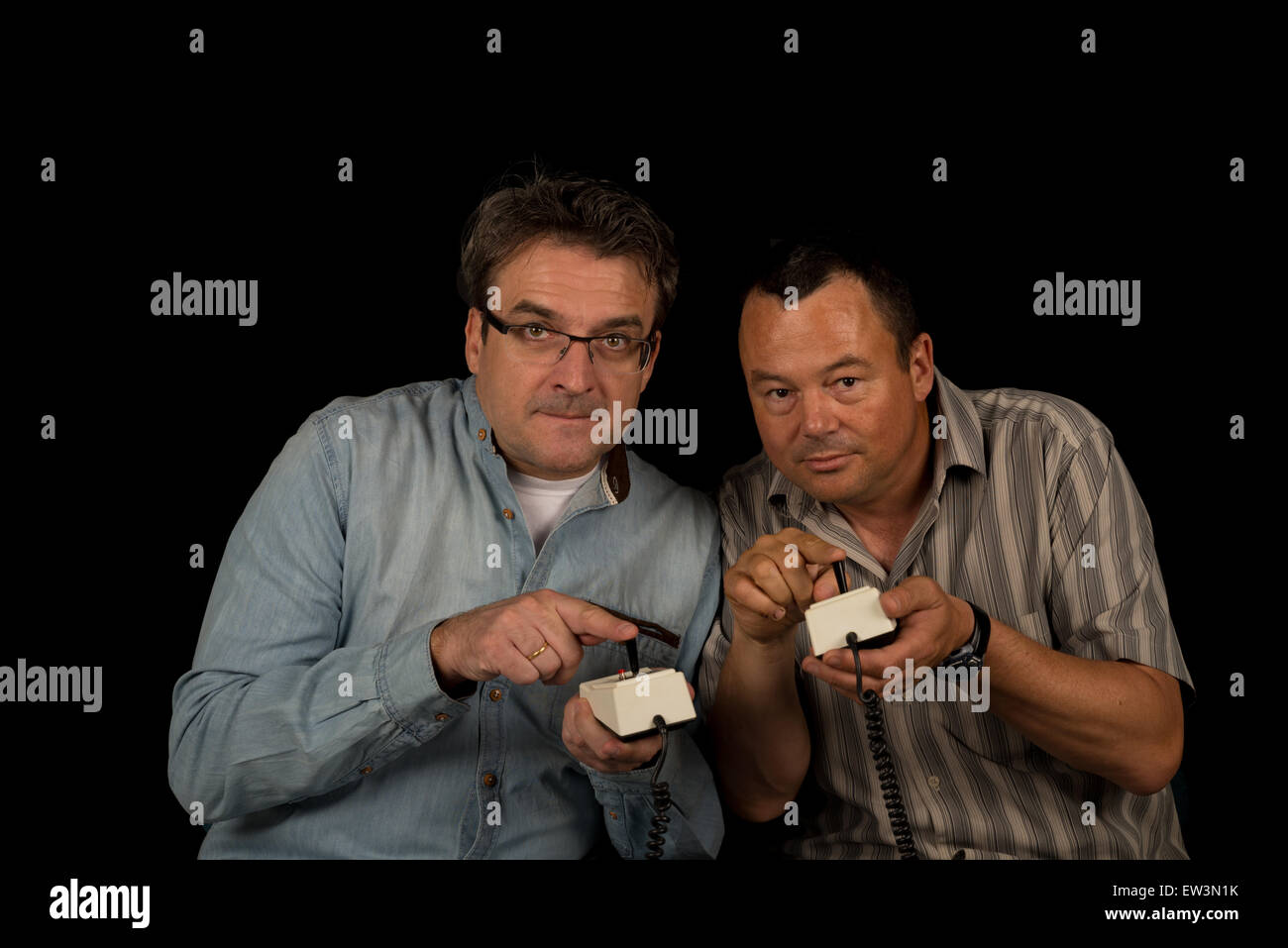 Two guys holding some retro video game controls Stock Photo - Alamy
