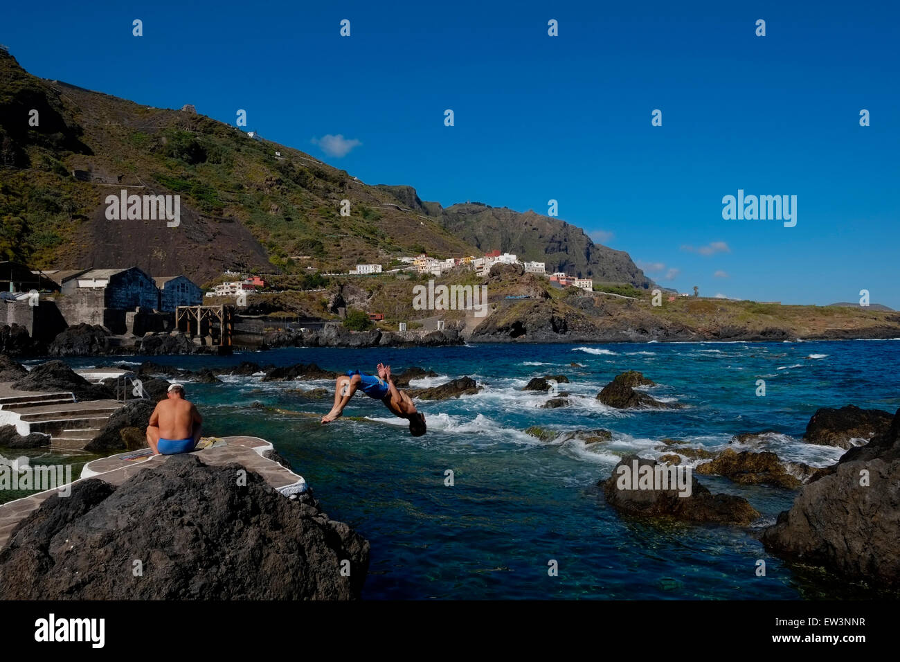 A young man leaps into the natural rock pools in the coast of the town ...