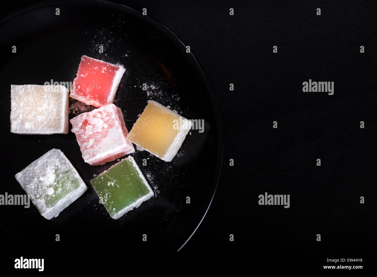 Turkish delight pieces on dark plate over black background Stock Photo ...