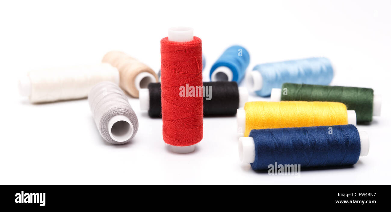 scattered different rainbow colored coils with threads on a white ...