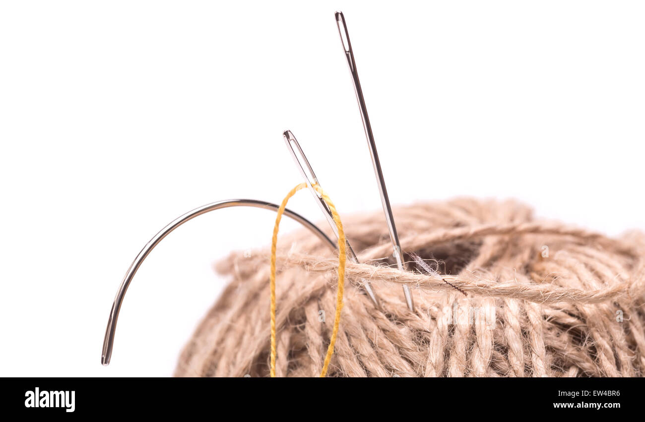 a needle stuck into the brown skein of thread on a white background Stock Photo - Alamy