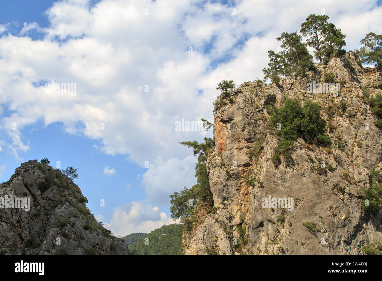 Bottom view of high mountains with small trees, on cloudy sky ...